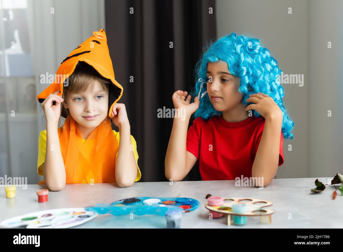 two little girls making crafts from autumn leaves for halloween at home ...