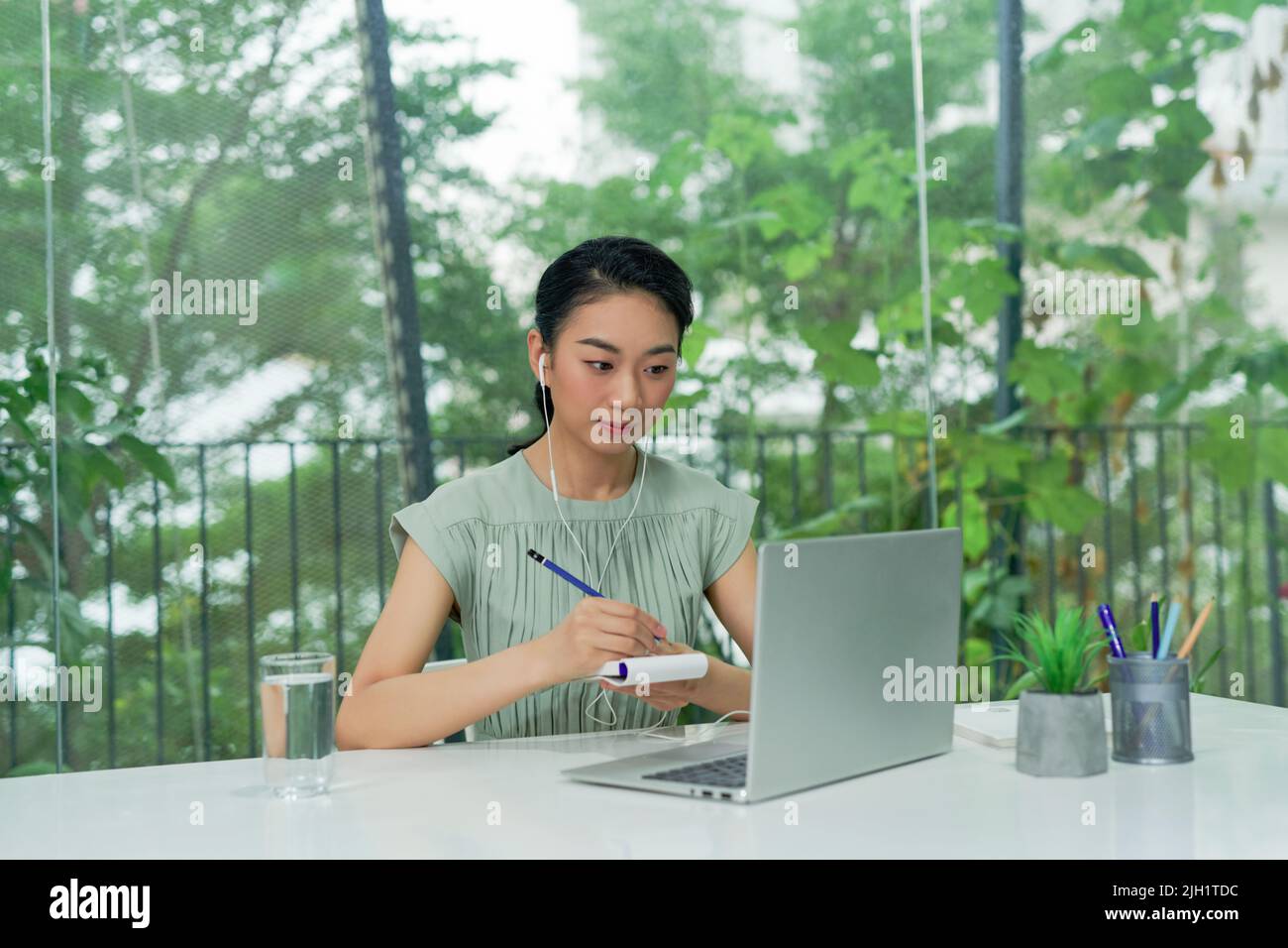 attractive cheerful young business woman write notebook look computer ...