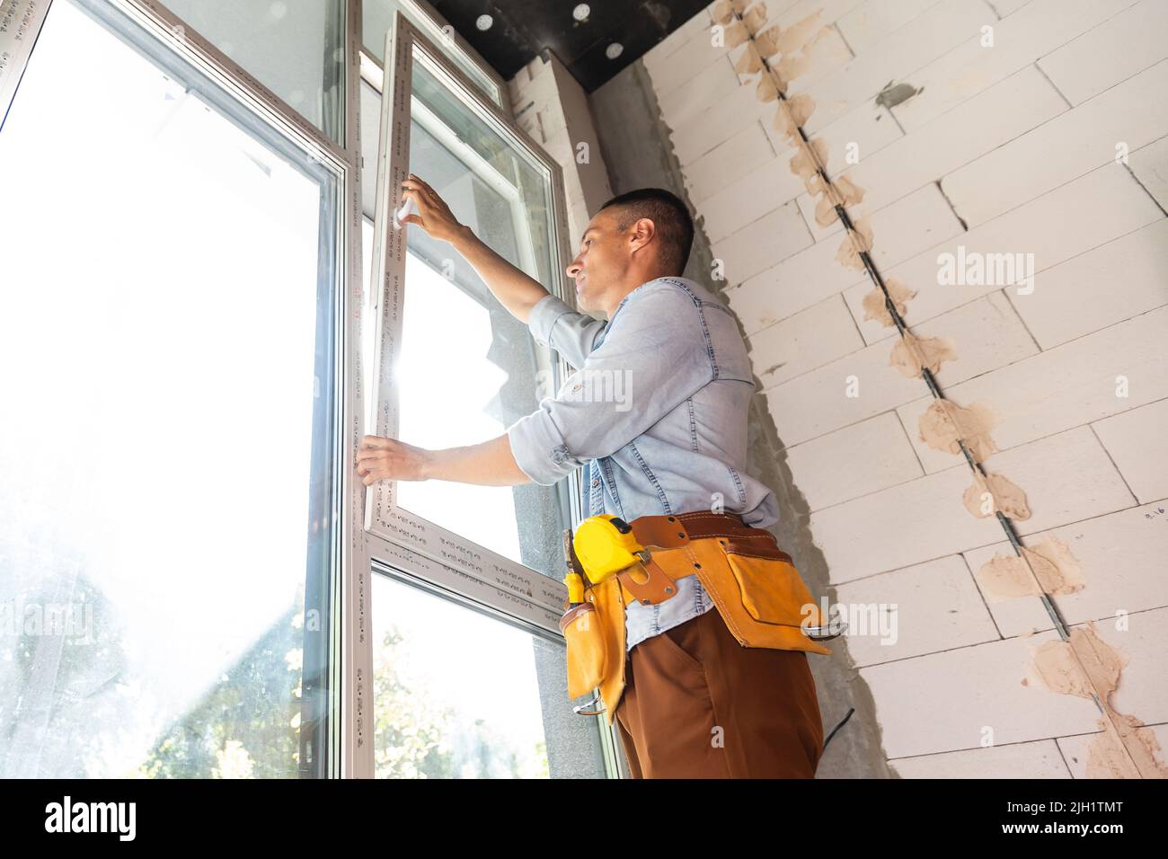 Construction worker installing window in house Stock Photo - Alamy