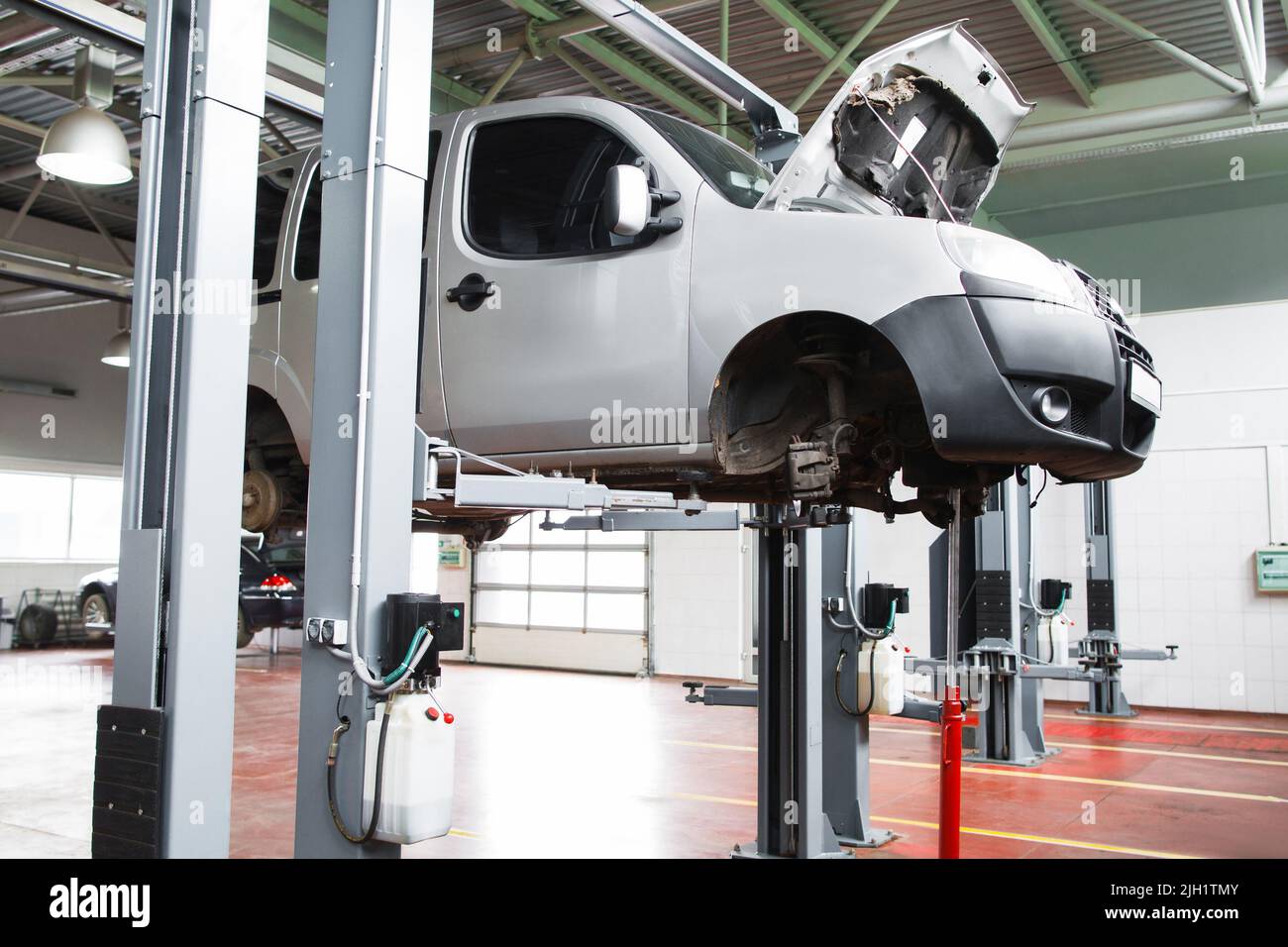 Car undergoing service in garage raised on lift Stock Photo - Alamy