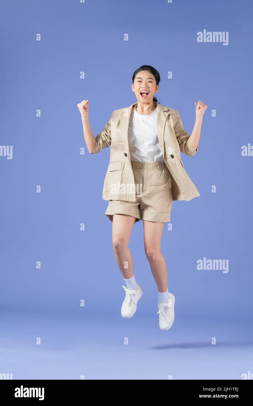 Energetic young asian woman jumping isolated on purple studio ...