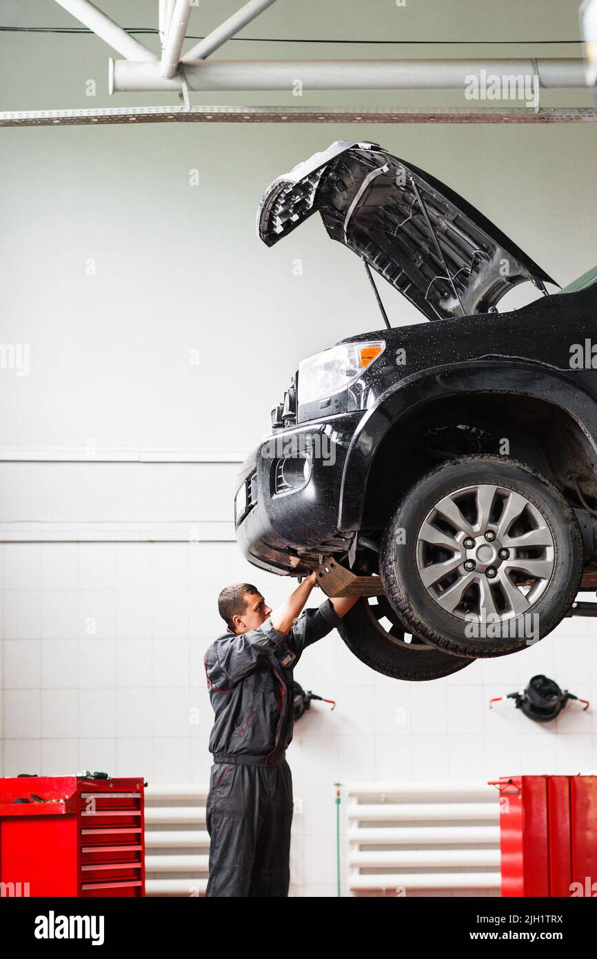 Mechanic working under car in service station Stock Photo - Alamy
