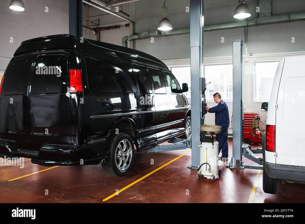Mechanic rising car on lift before maintenance Stock Photo - Alamy
