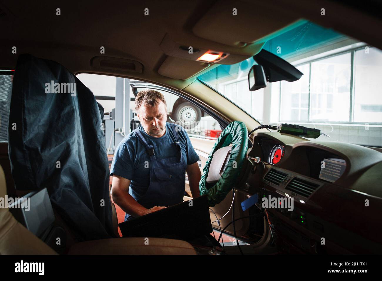 Professional serviceman checking car with computer Stock Photo - Alamy