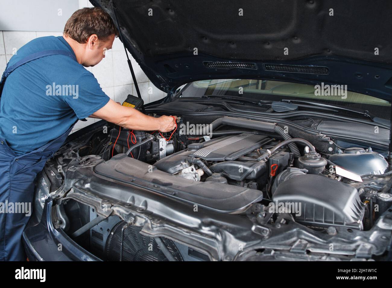 Electrician testing car with multimeter at garage Stock Photo - Alamy
