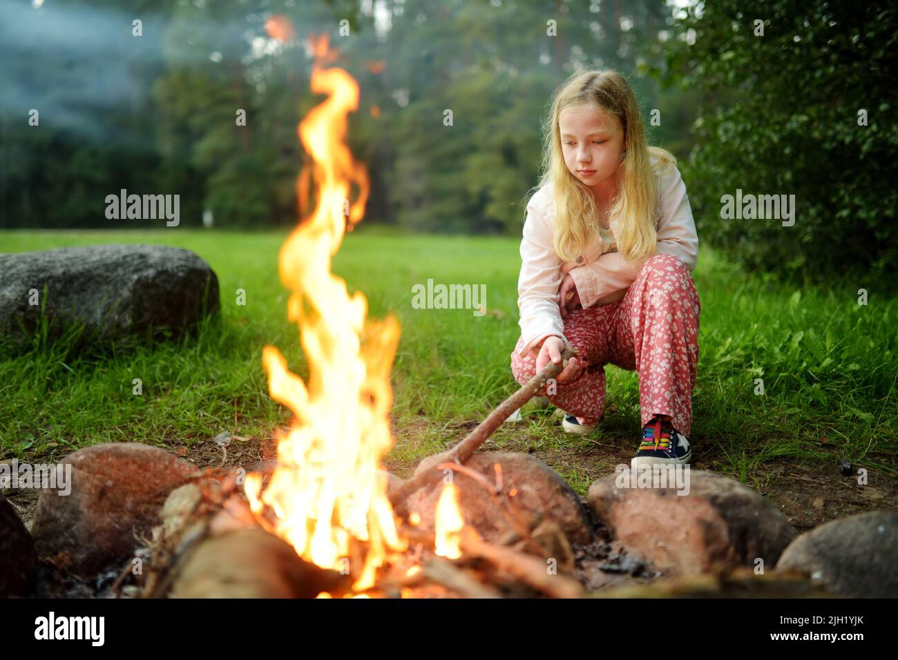 Cute young girl having fun by a bonfire. Having fun at a camp site with ...