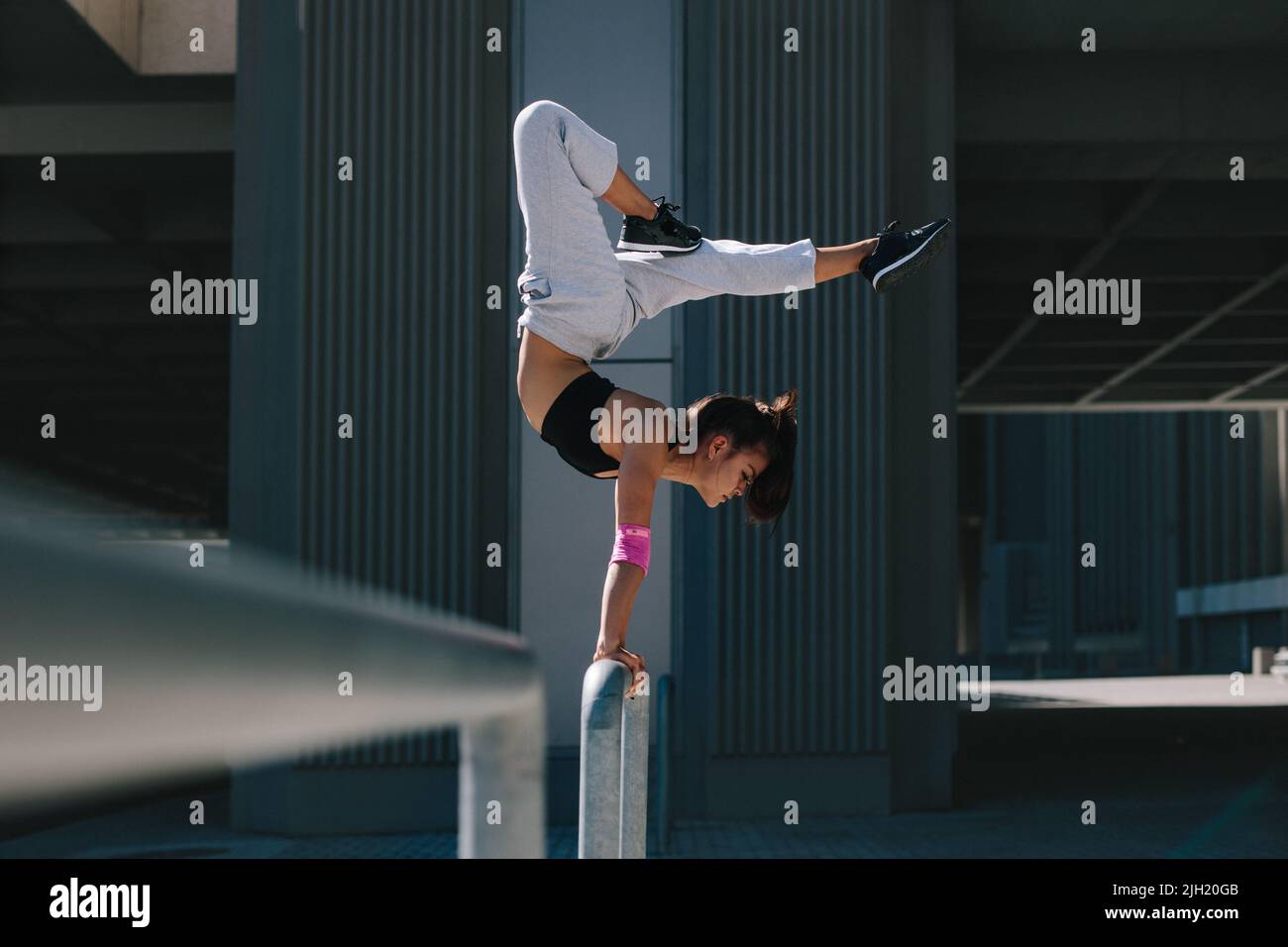 Sportswoman doing a handstand on railing outdoors. Flexible female ...