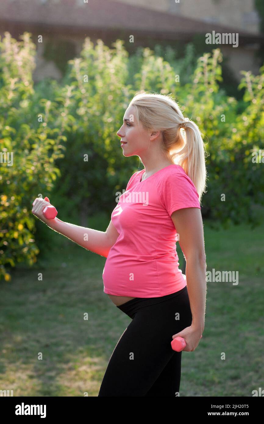 Side view on pregnant woman with dumbbells Stock Photo - Alamy