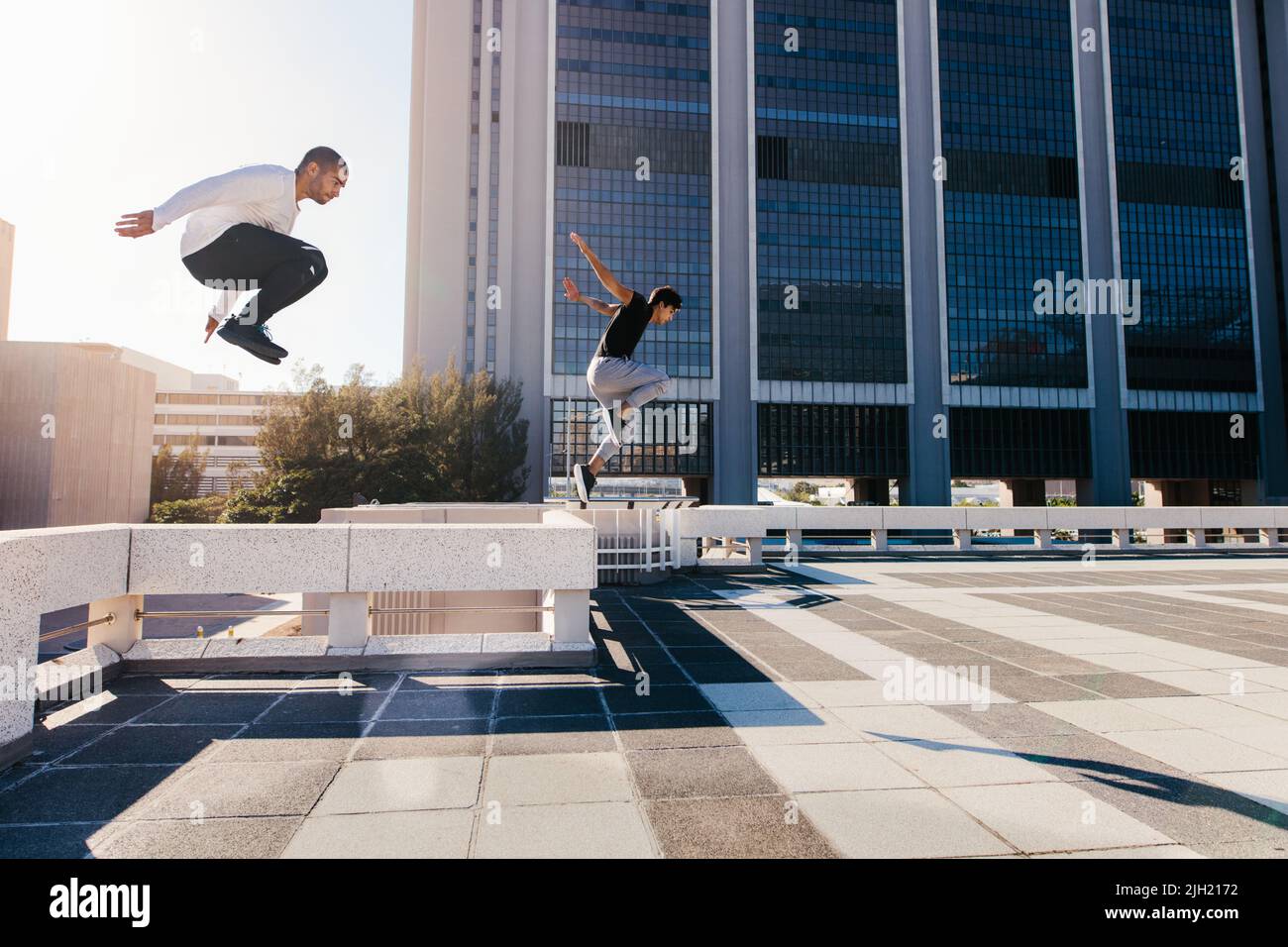 Two young sportsmen practicing parkour against a city background. Young ...