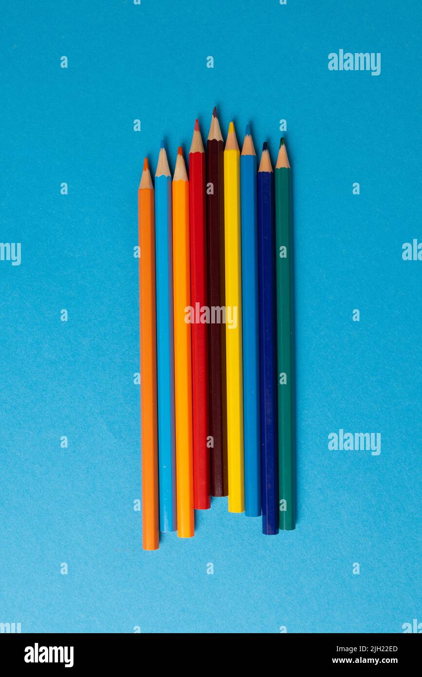 Vertical composition of colorful crayons on blue surface with copy ...