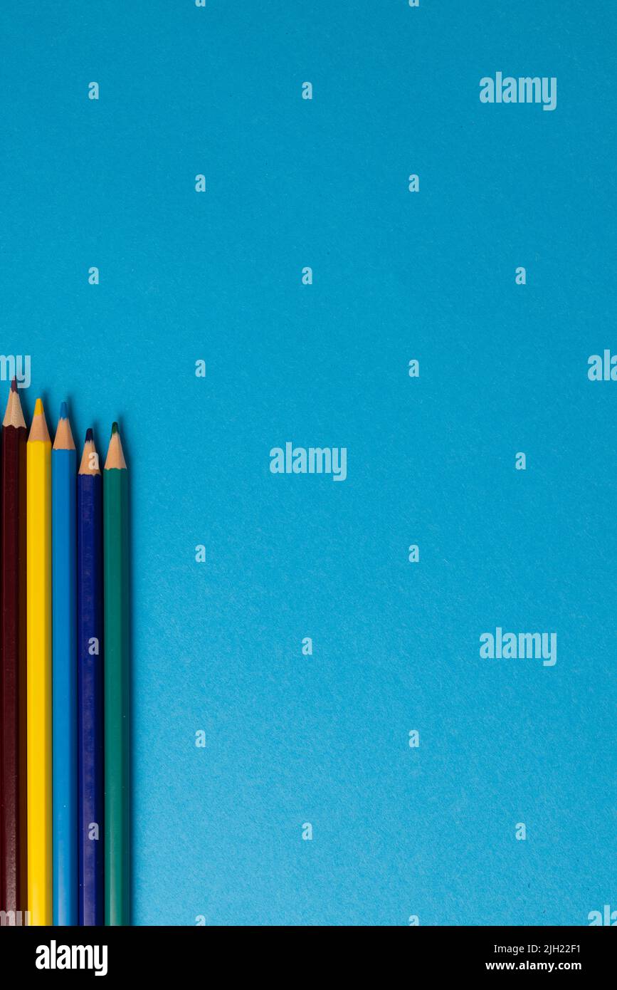 Vertical composition of colorful crayons on blue surface with copy ...