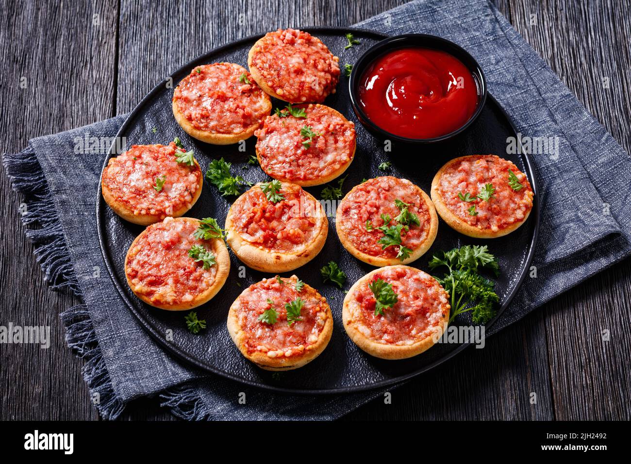 mini pizzas, piccolinis, with ham and pecorino cheese on black plate ...