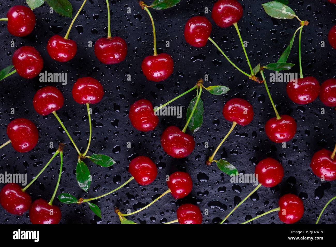 background of ripe wet cherries with water drops on a black background ...