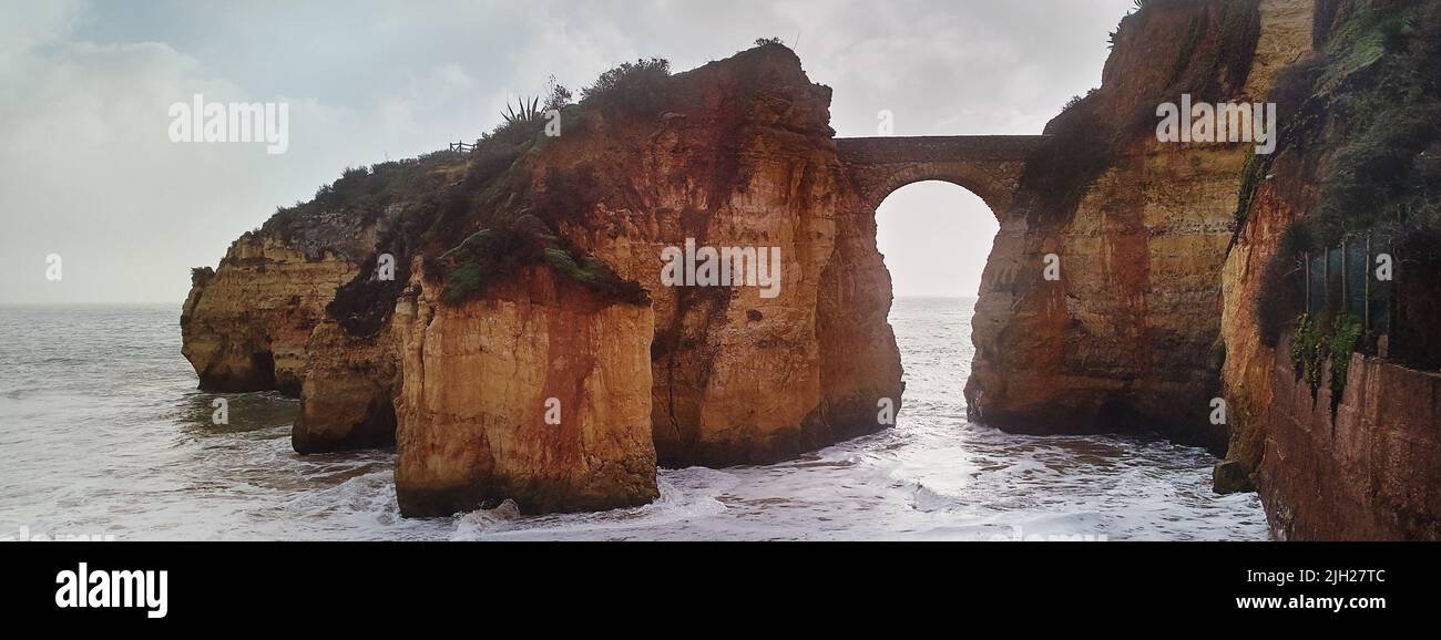An arch link one of the rocks with the mainland landscape during cloudy ...