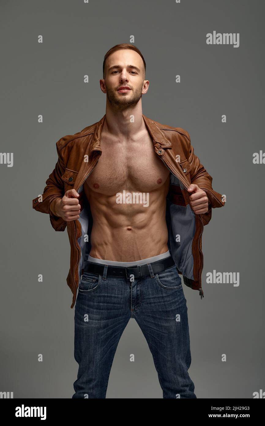 An attractive white man in jeans and black shirts tands in full growth ...