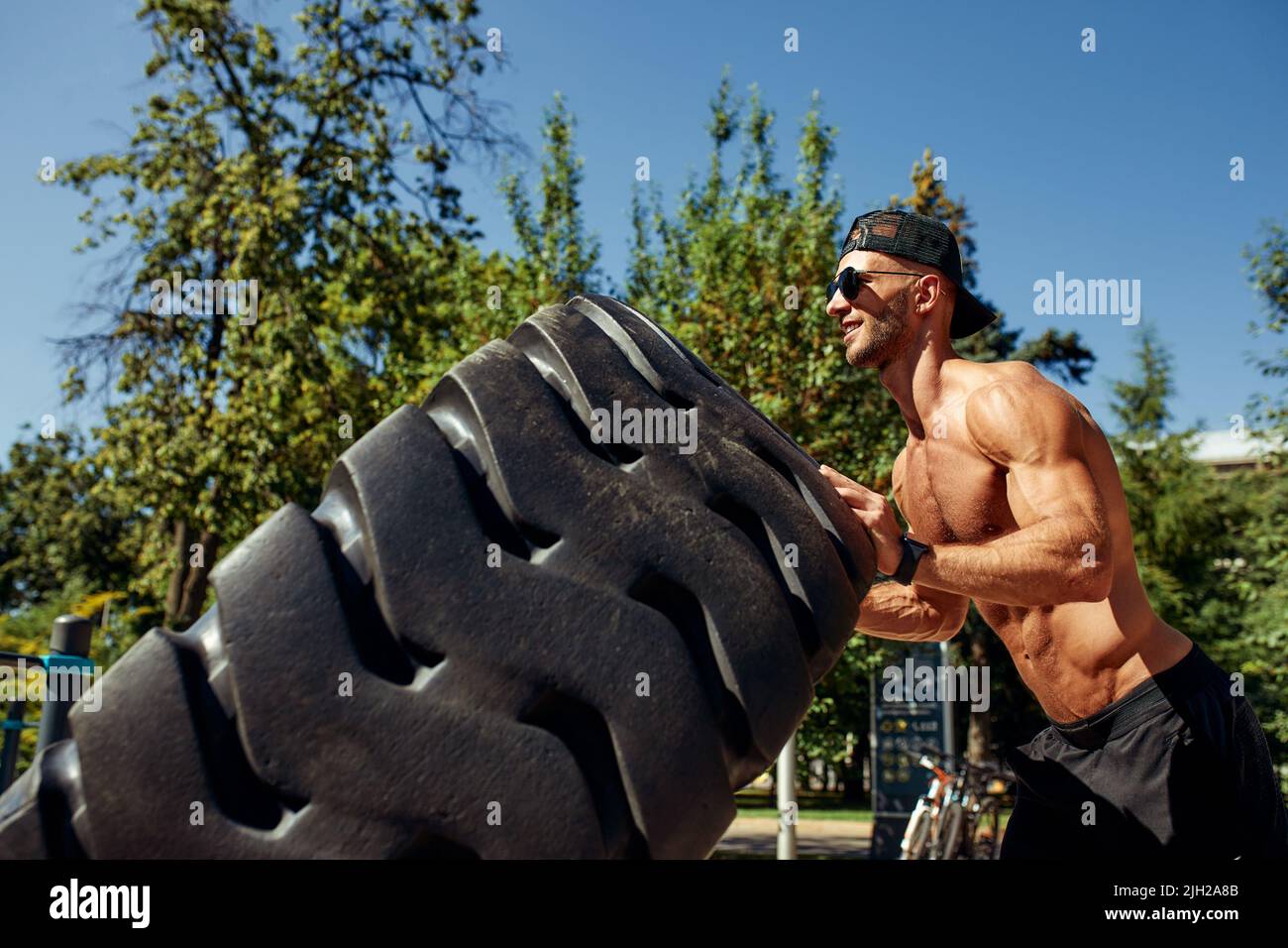 Strong man training workout lifting large tire outdoor gym. Sportive ...