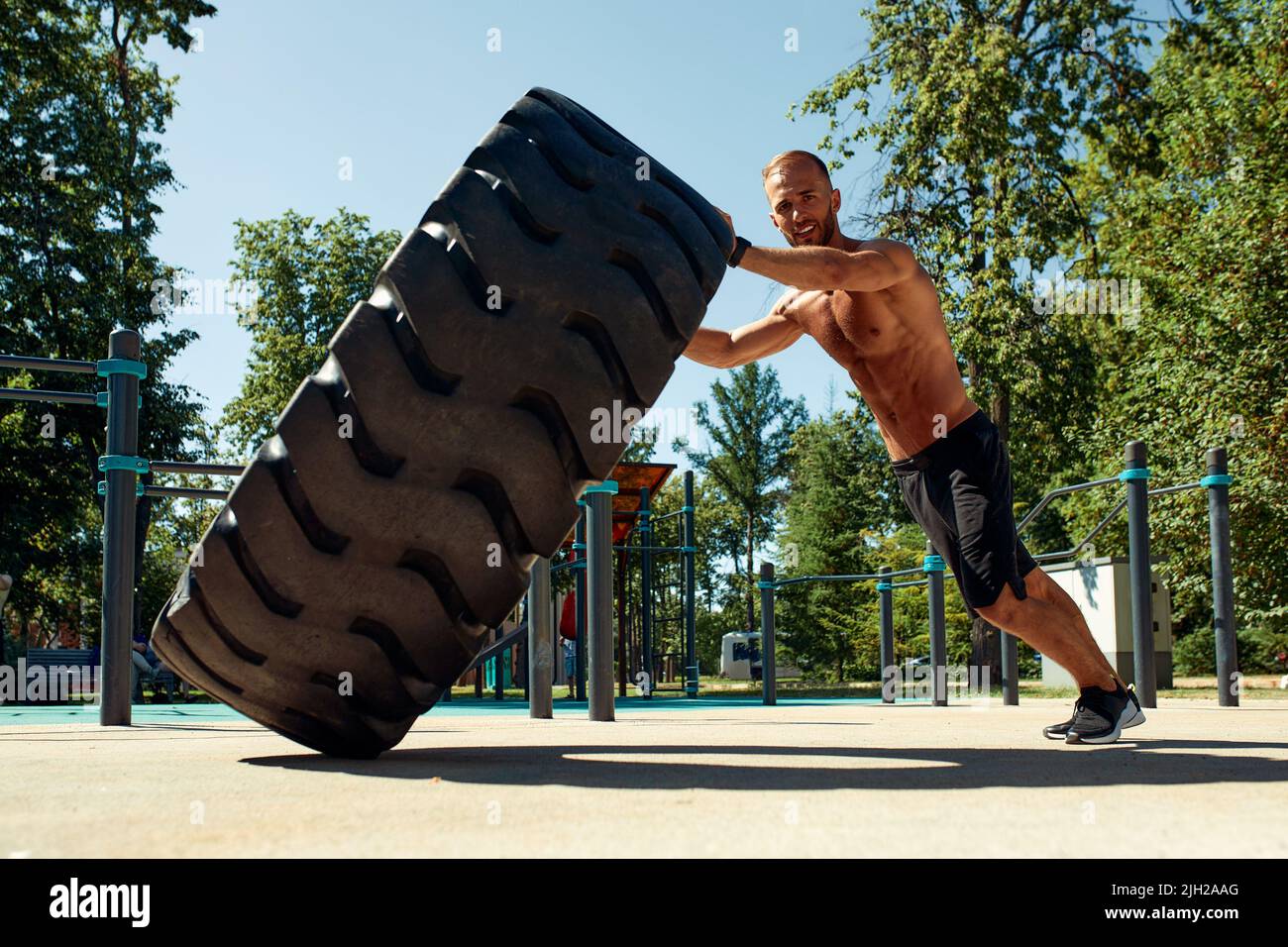 Strong man training workout lifting large tire outdoor gym. Sportive ...