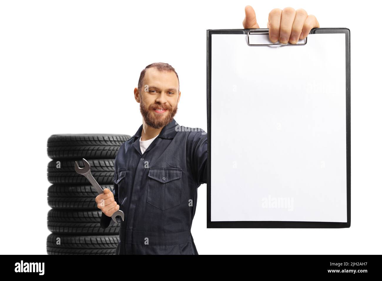 Car mechanic in a uniform holding a wrench and a blank paper with a ...