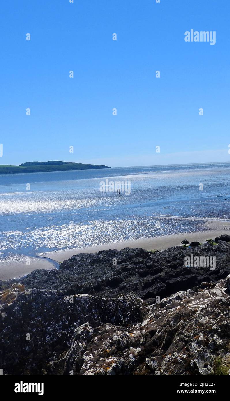 Vertical photograph of two lone walkers crossing the beach at Dhoon Bay ...