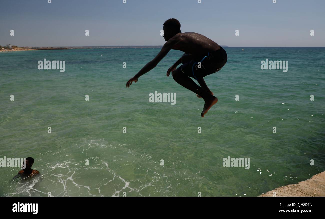Palma, Spain. 14th July, 2022. Gerry, a Mallorcan boy, jumps into the ...