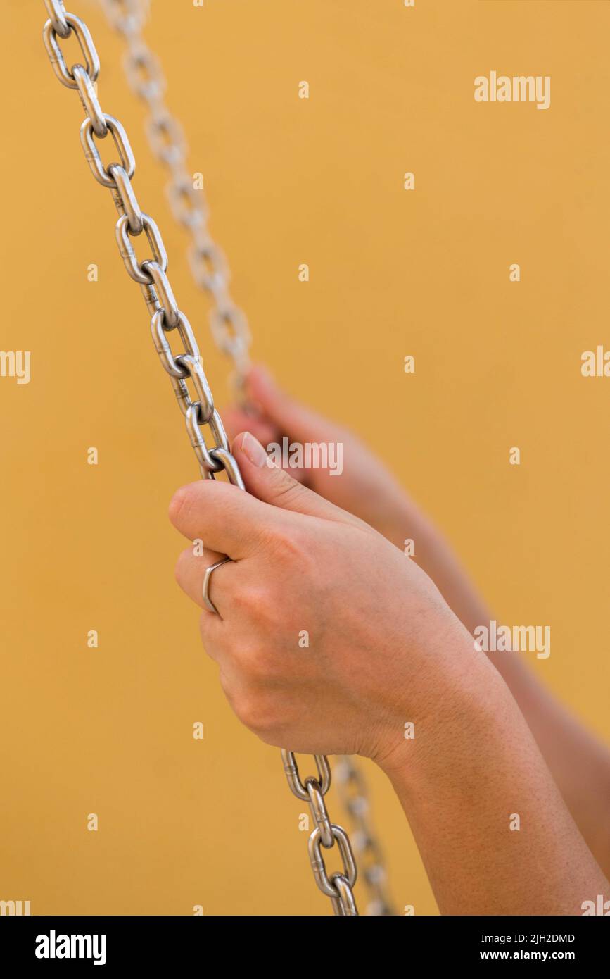Hands holding swing chain on a yellow background Stock Photo - Alamy
