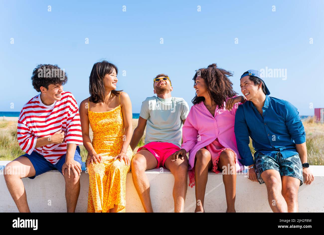 Multiethnic group of young happy friends bonding outside, having fun on summertime vacation ...