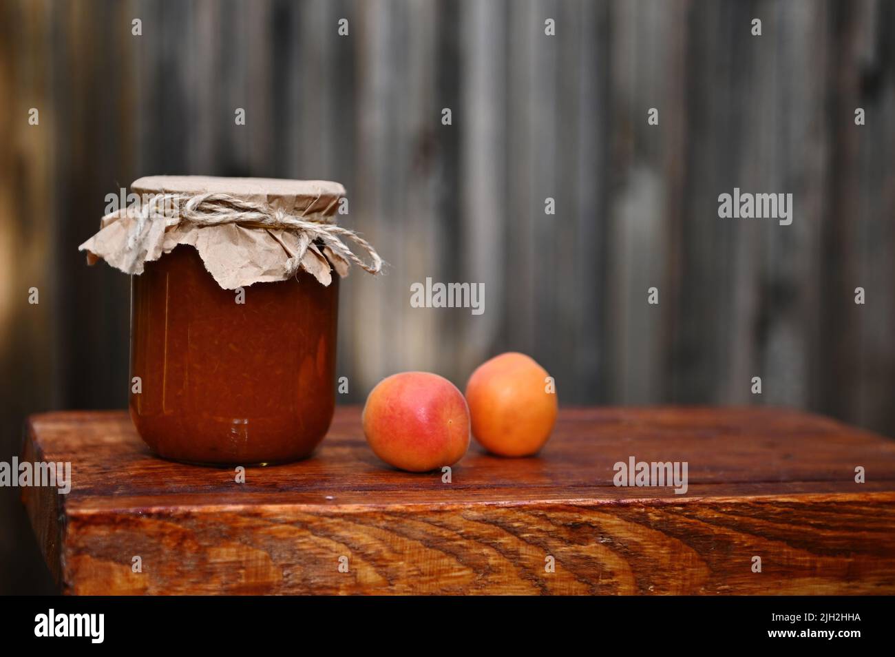 A jar of homemade apricot jam with lid decorated with craft paper and ...