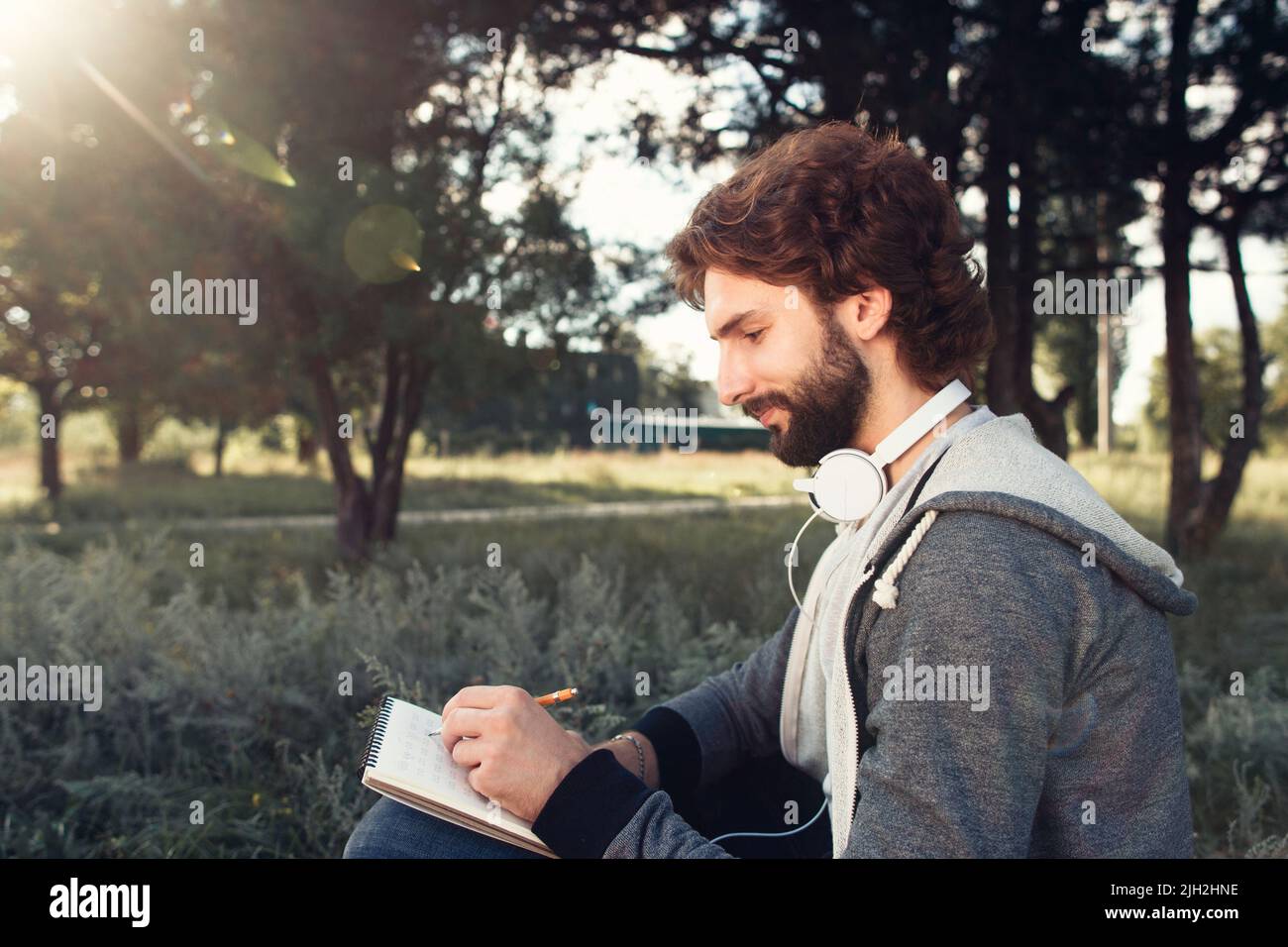 Young man writing in notebook at nature, side view Stock Photo - Alamy