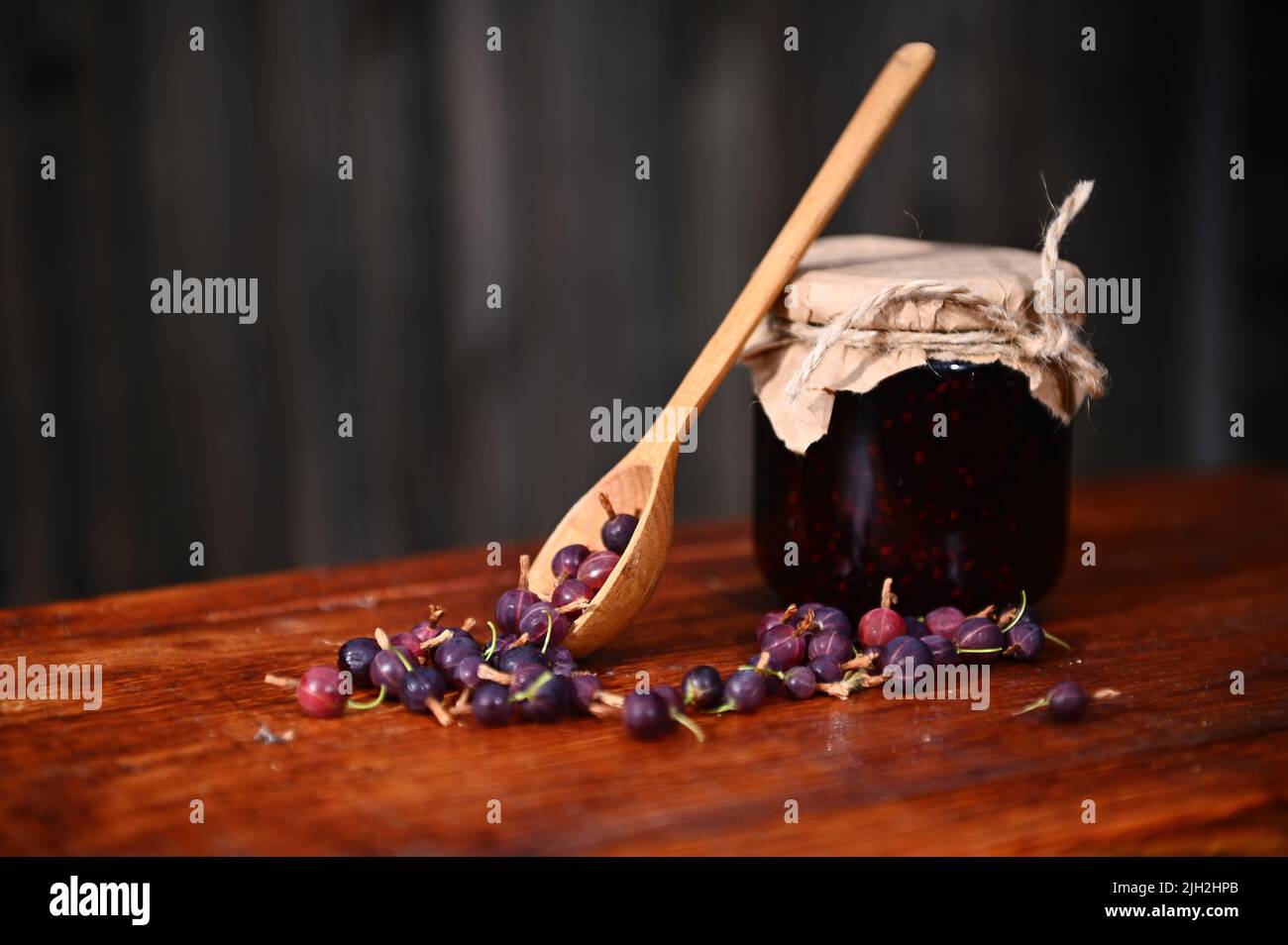 Still life. Jar of homemade berry jam, wooden spoon and gooseberries on ...