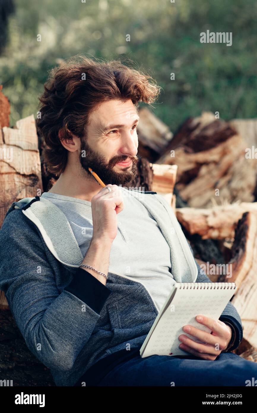 Thinking guy with notebook on pile of wood Stock Photo - Alamy