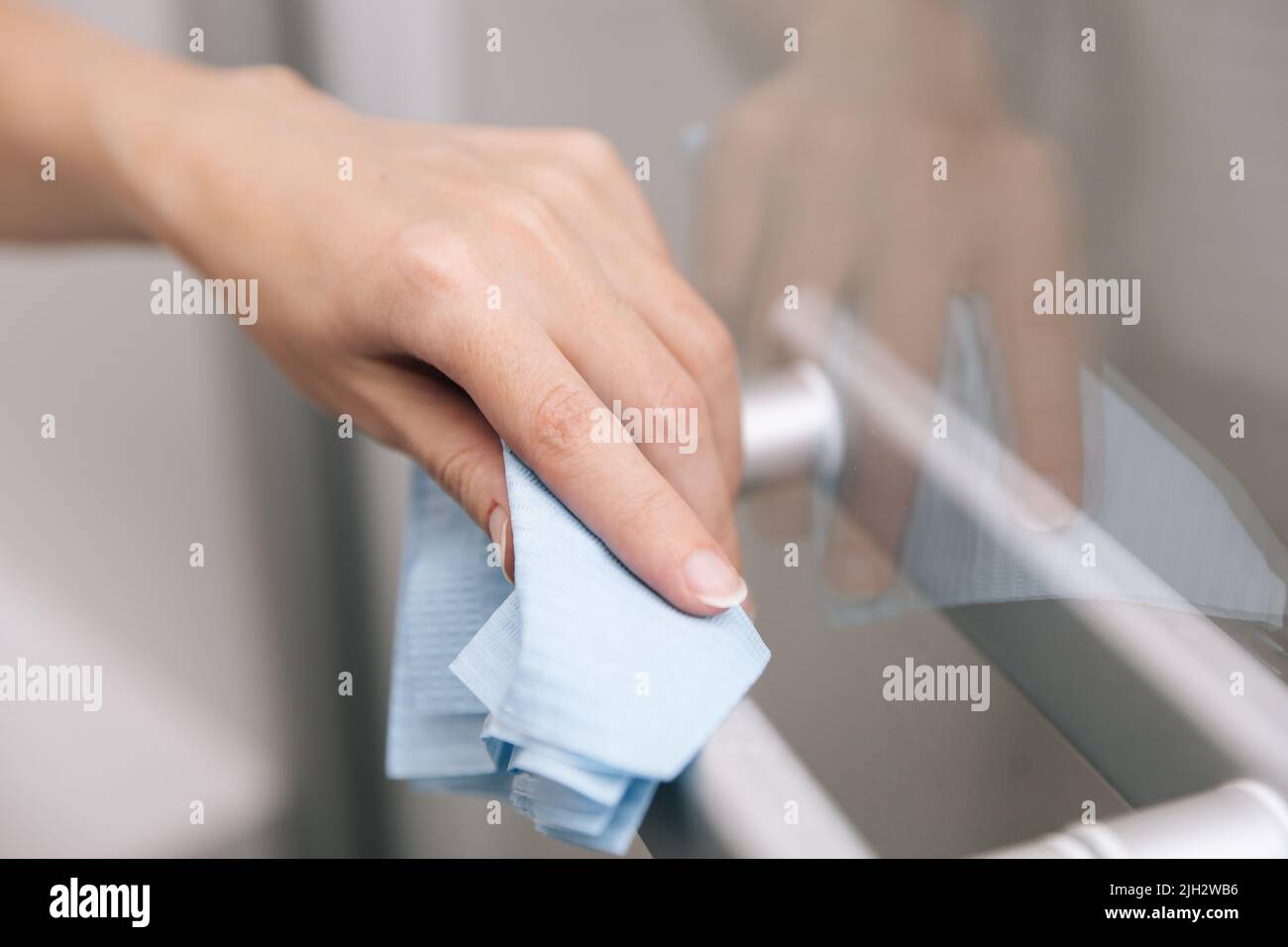 Cleaning glass door handles with an antiseptic wet wipe. Sanitize ...