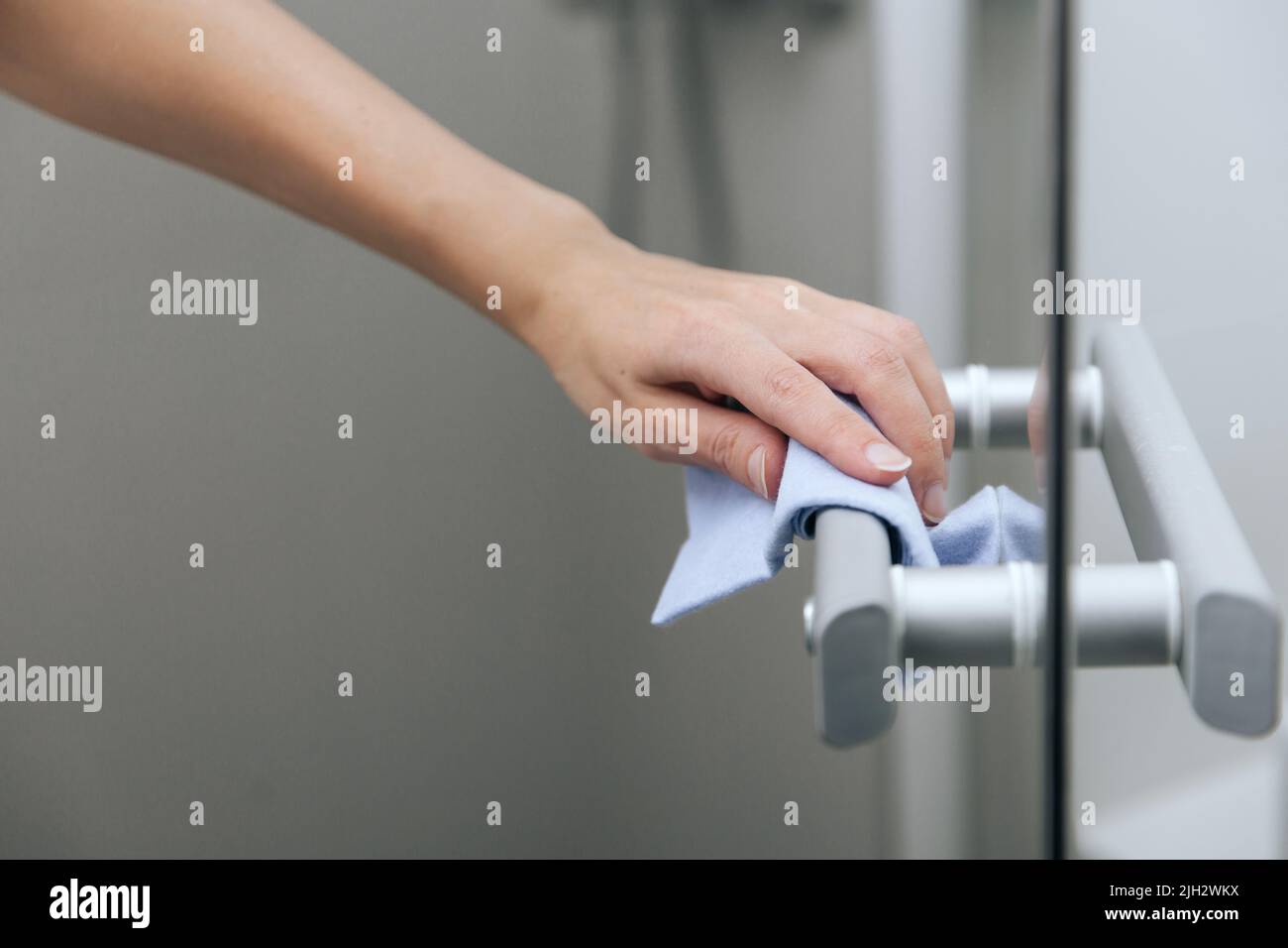 Cleaning glass door handles with an antiseptic wet wipe. Sanitize ...