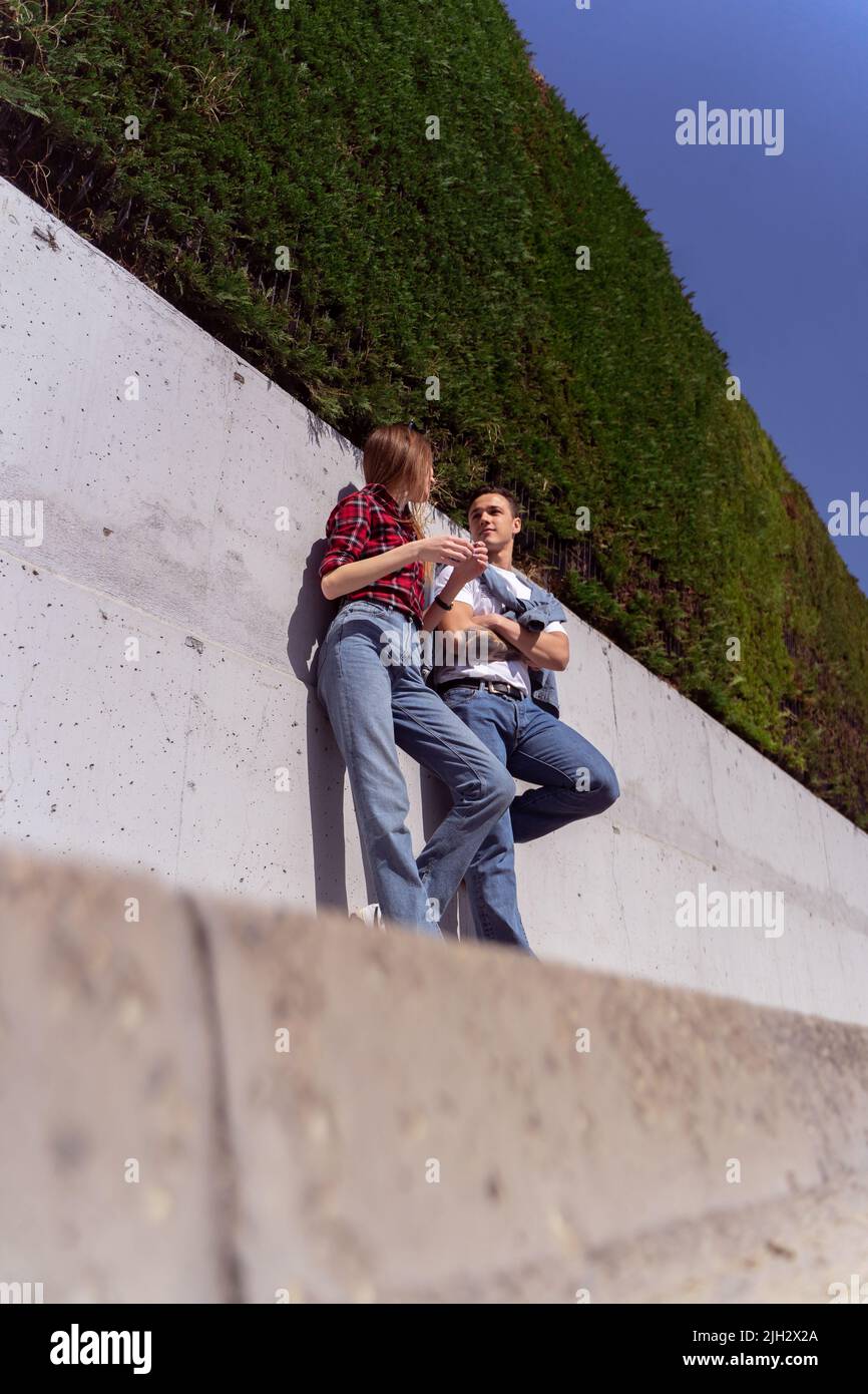 Cute couple hanging out while leaning on the wall Stock Photo - Alamy