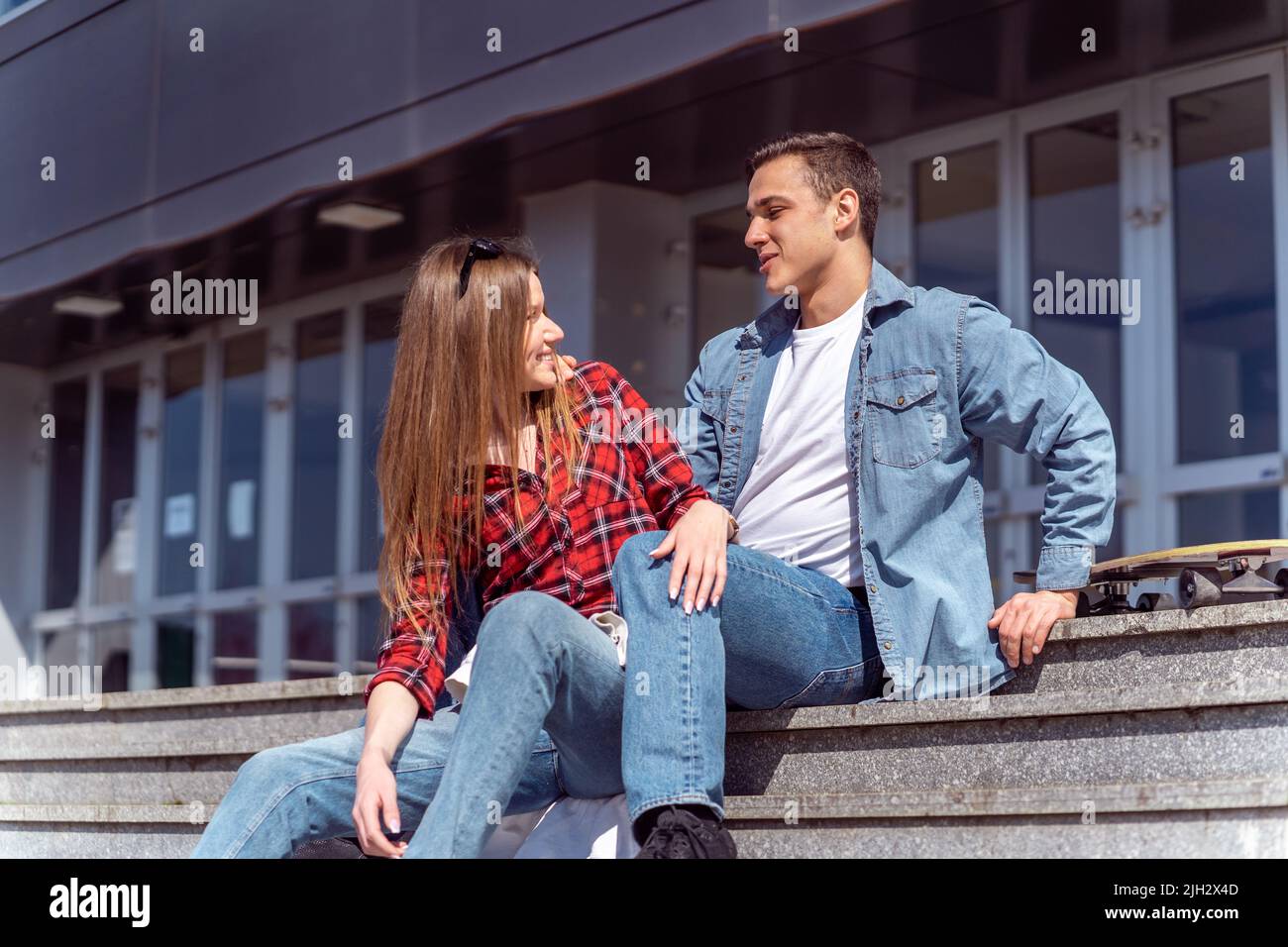 Cute couple talking while sitting on the stairs Stock Photo - Alamy