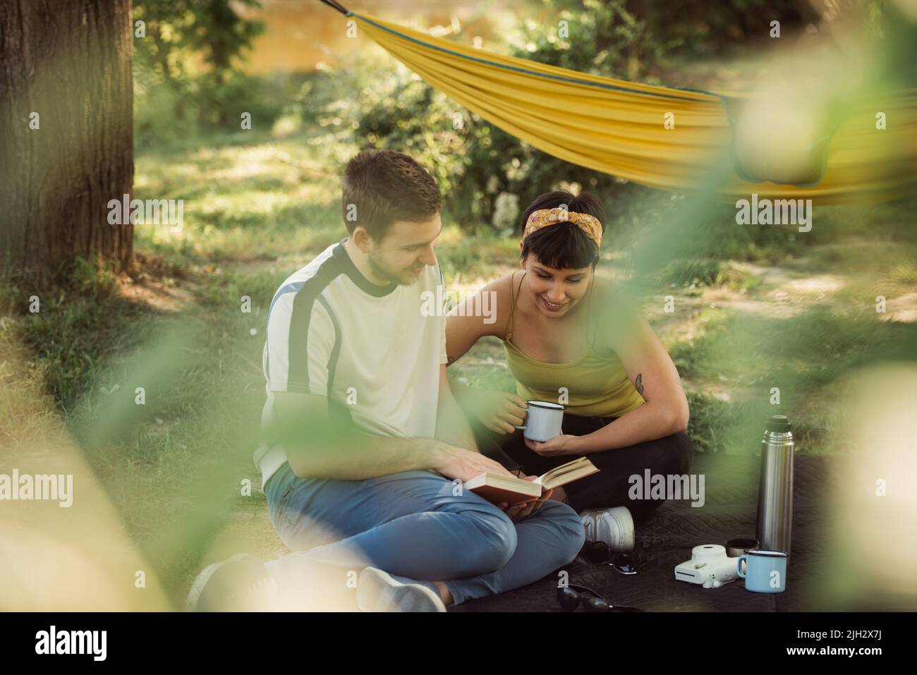 Pretty couple reading a book together while sitting on a picnic in the ...