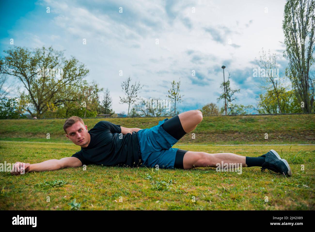 Attractive Man In His 20s In Sportswear Stretching His Leg Muscles