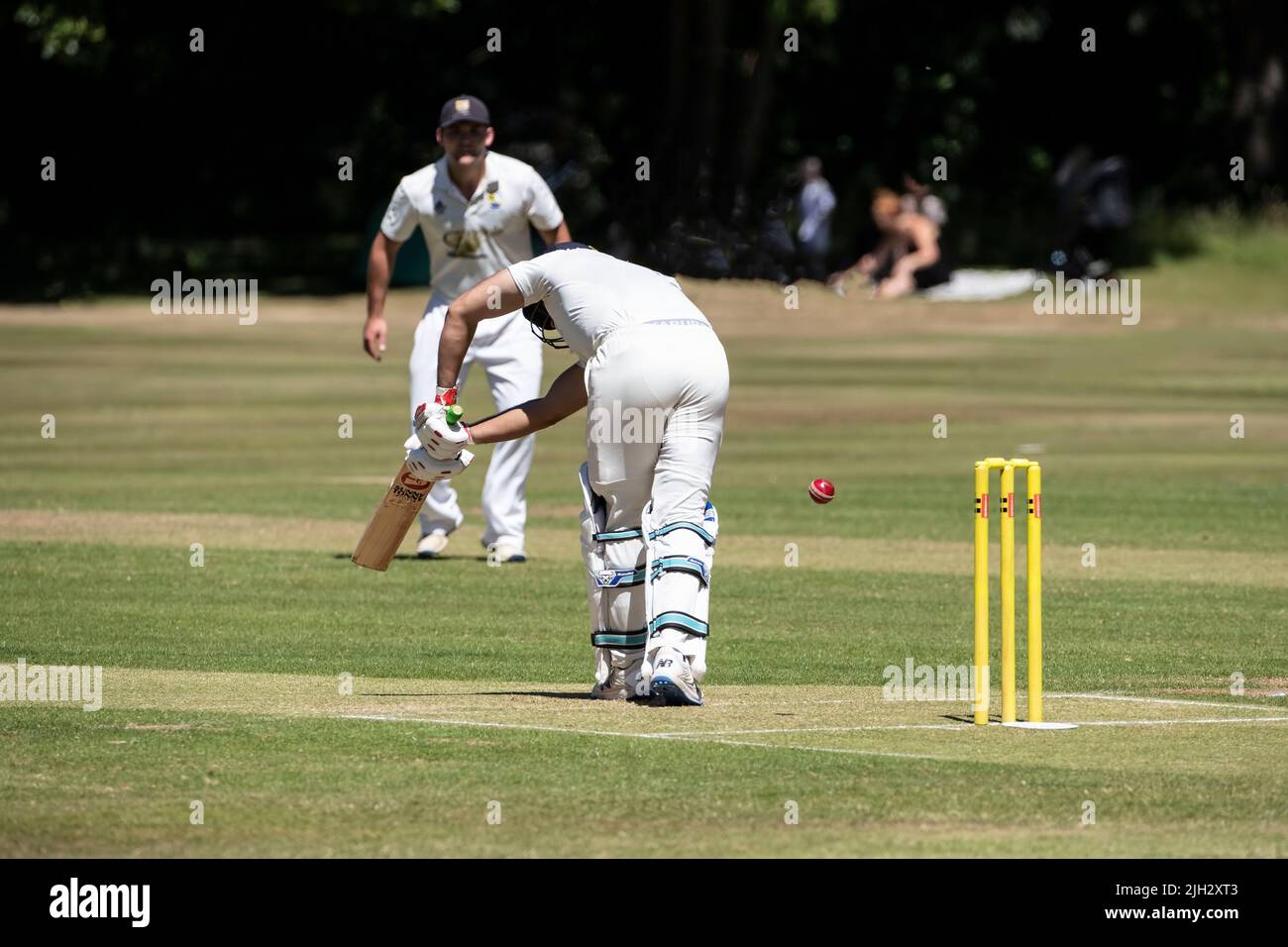Batsman steers the ball to the leg side watched by a close fielder in a ...