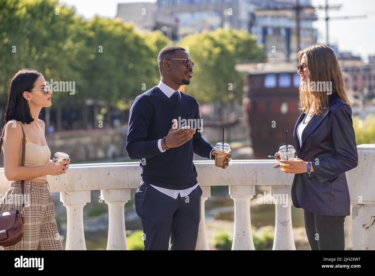 Three multiracial business co workers are talking while smiling on ...