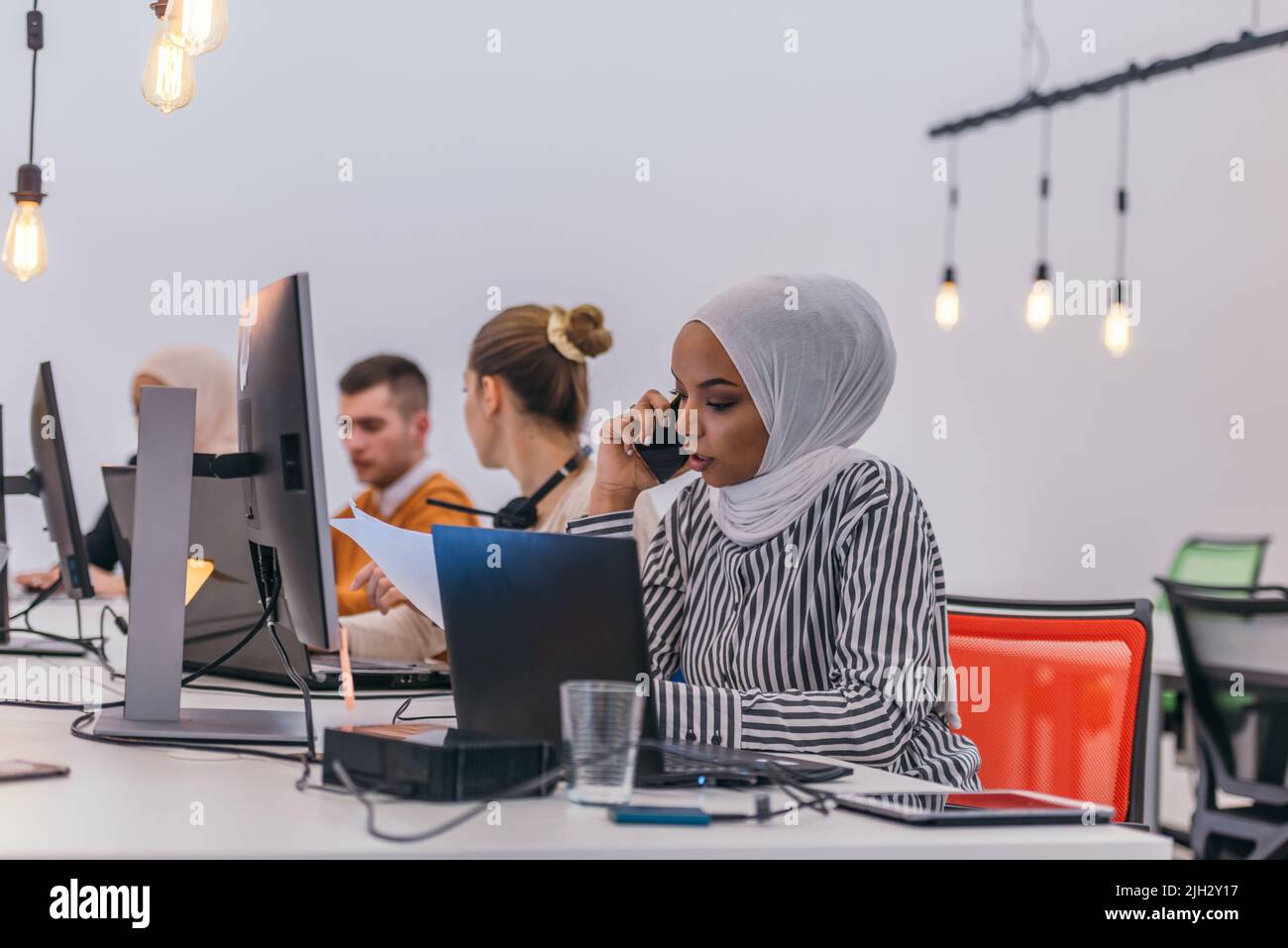 An african female employee with white hijab answering client's ...
