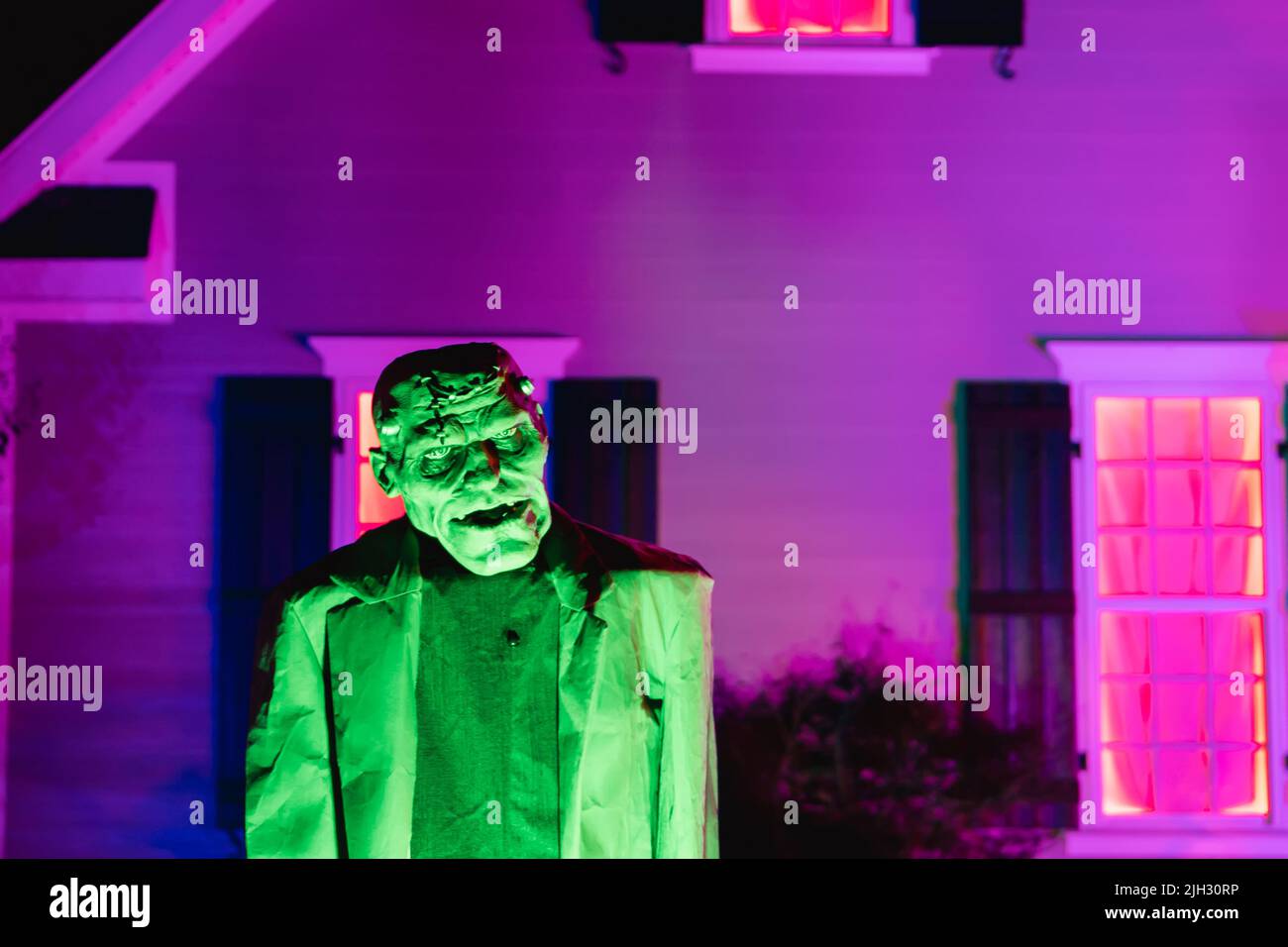 A scary life sized Frankenstein snimated monster glowing green against ...