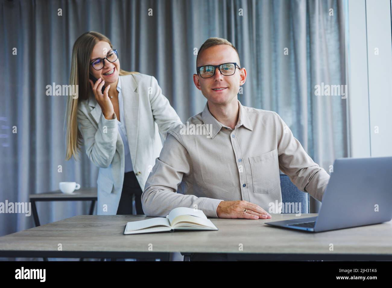 A business woman in front of a male colleague who works at a laptop ...