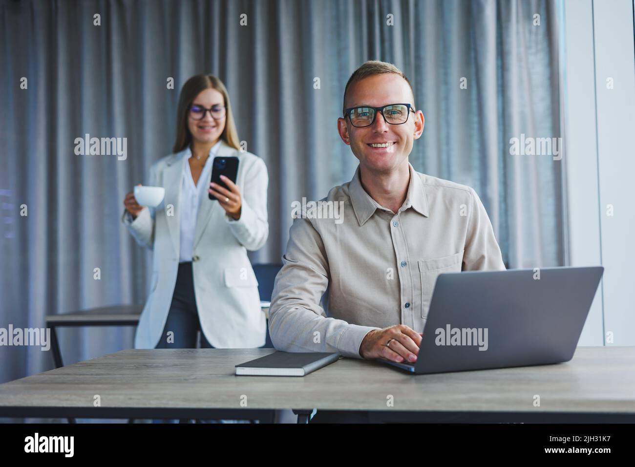 A business woman in front of a male colleague who works at a laptop ...
