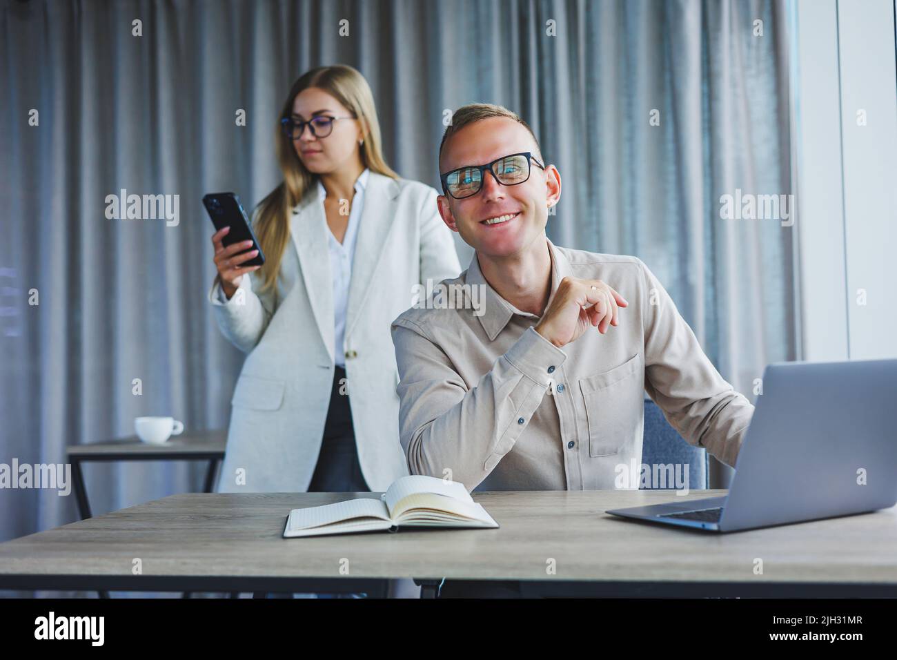 A business woman in front of a male colleague who works at a laptop ...