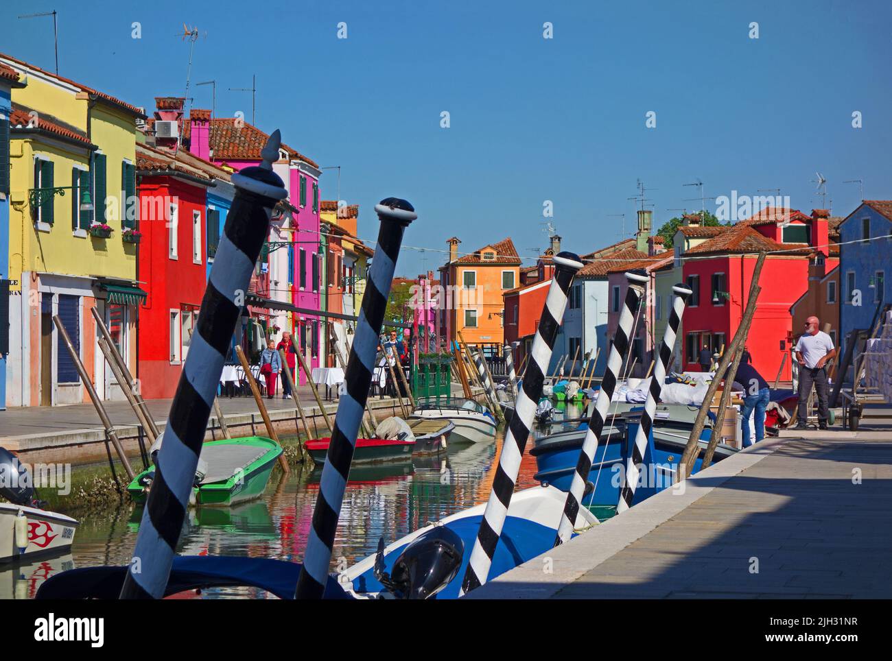 VENICE, ITALY - APRIL 20, 2019 boat mooring posts and brightly painted ...