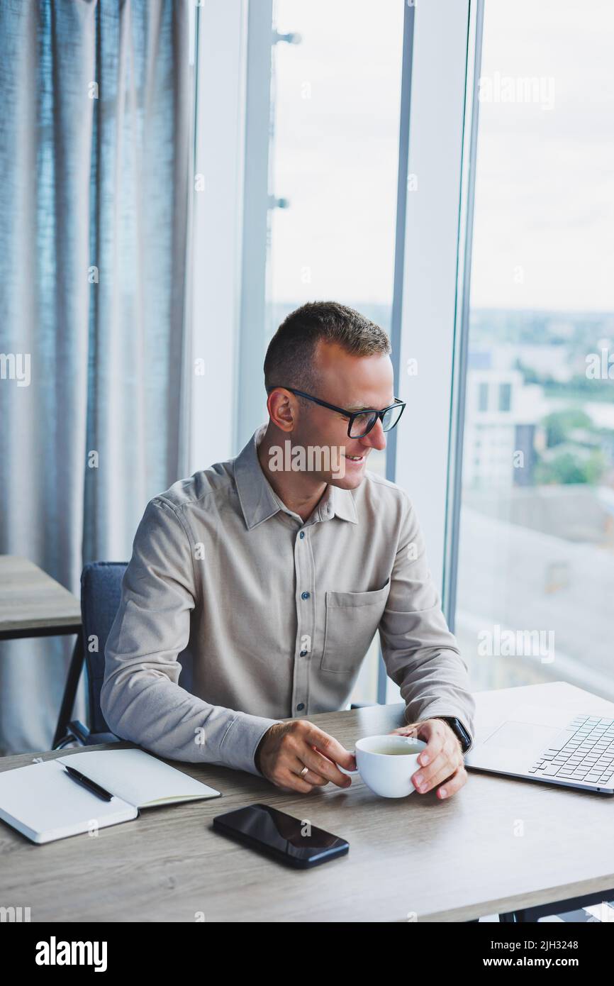 A businessman works on a laptop, a manager sits at a table in the ...