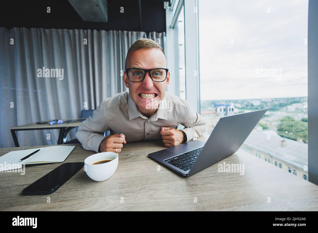 Emotional man looking at the camera at the workplace, a man in glasses ...