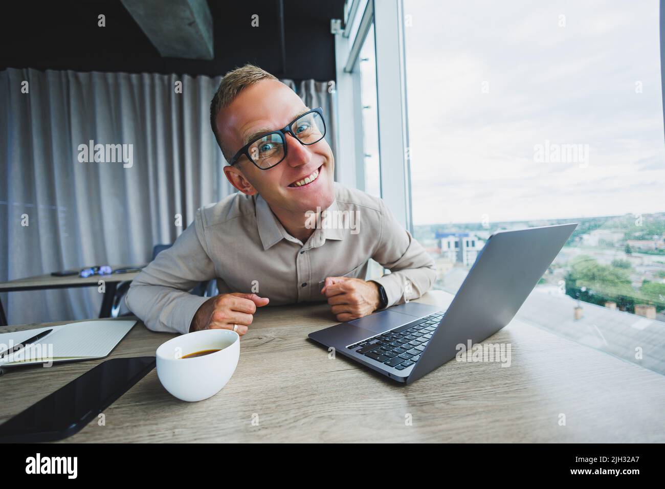 Emotional man looking at the camera at the workplace, a man in glasses ...