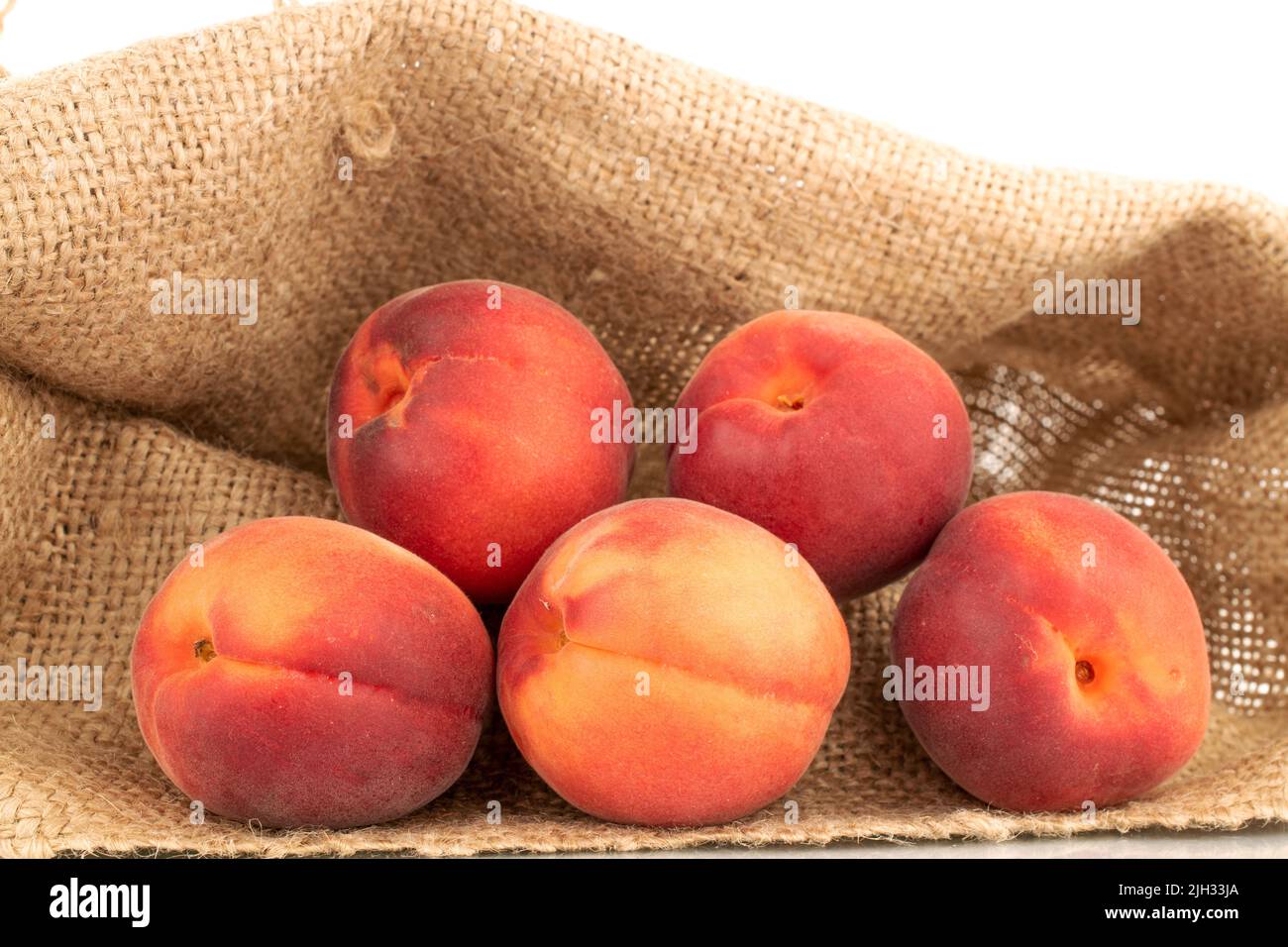Several ripe red apricots with a jute sack, close-up, isolated on a ...