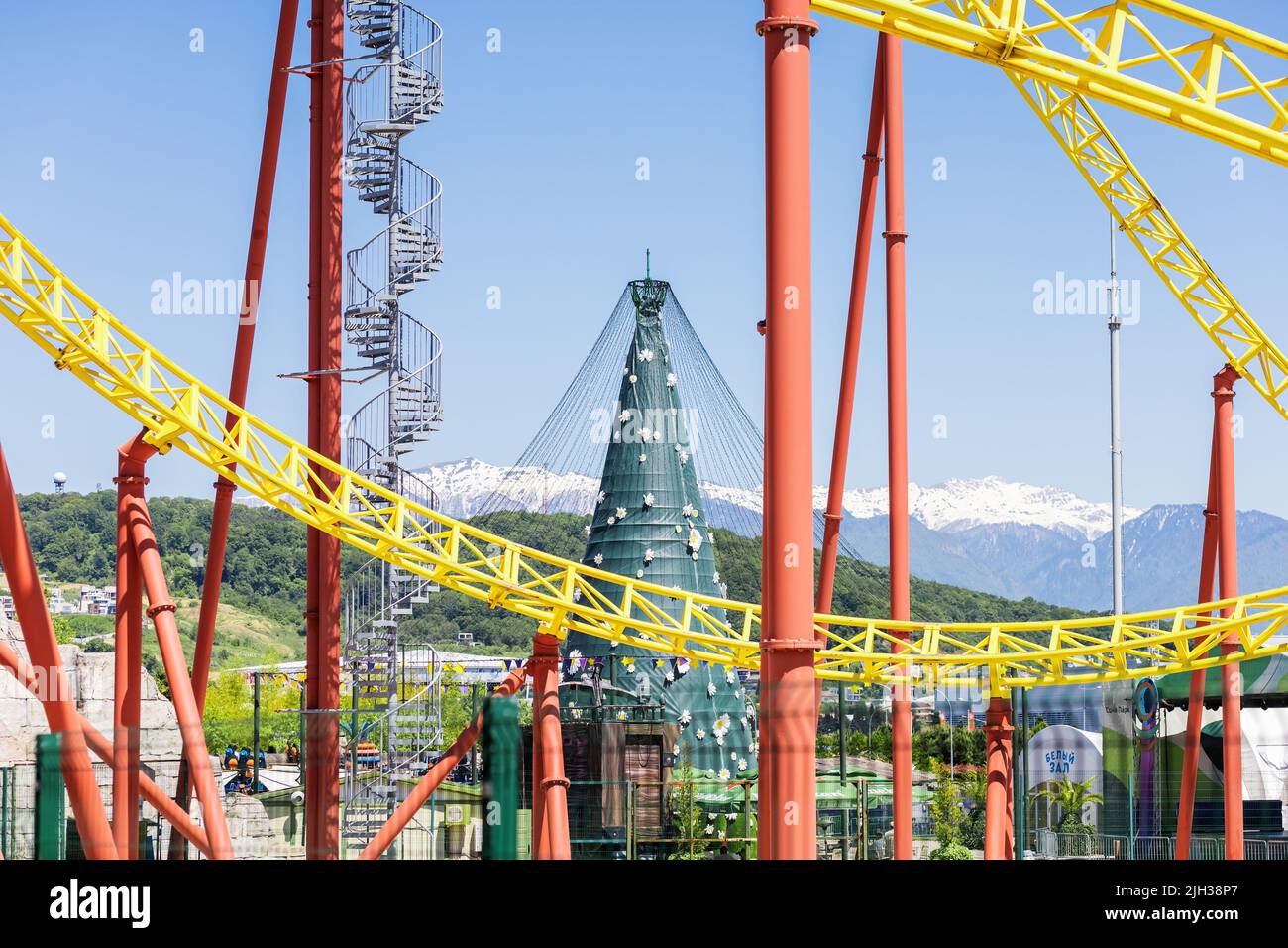 Roller coaster in amusement park against the backdrop of green hills ...