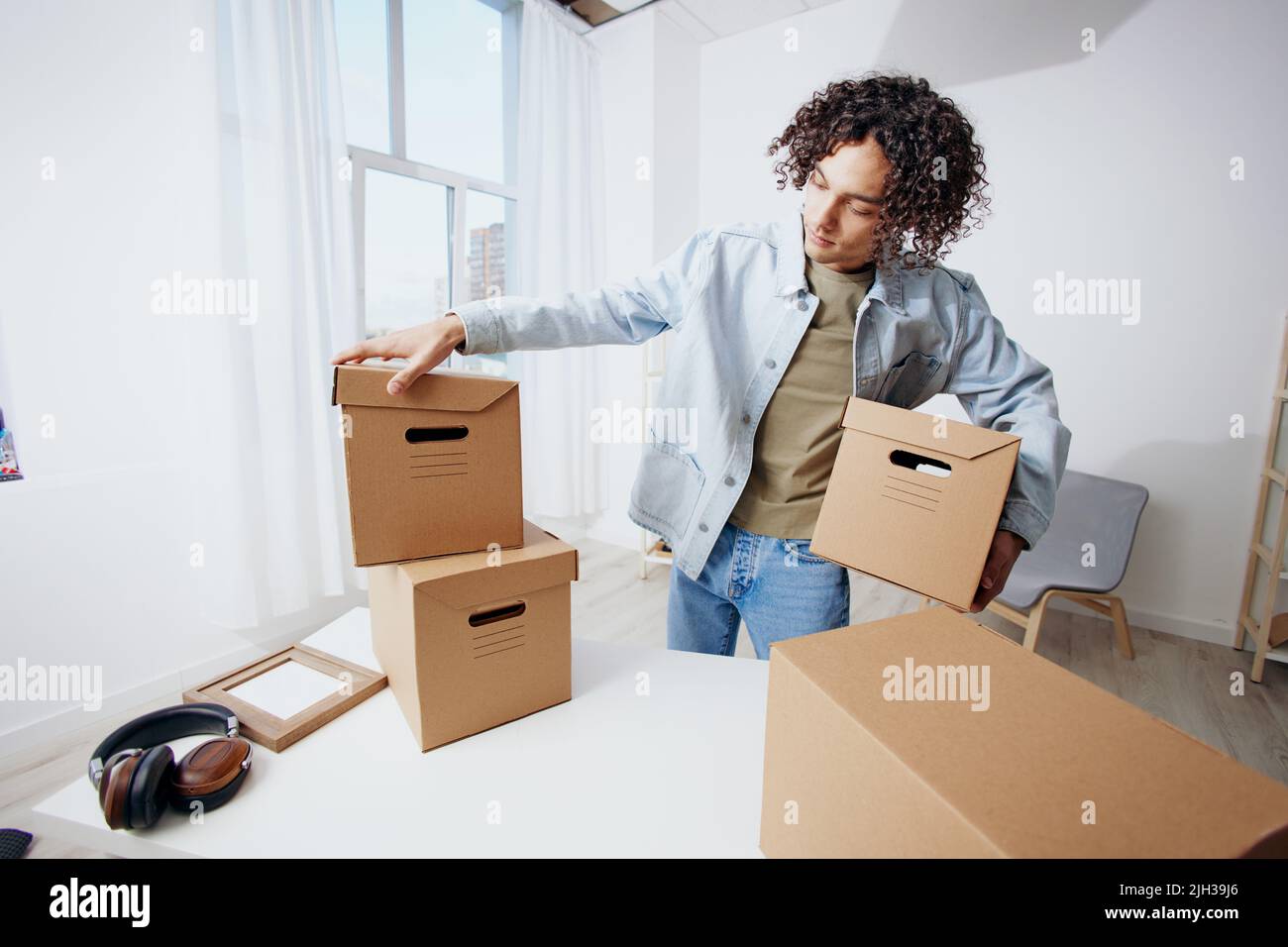 A young man unpacking things from boxes in the room interior Stock ...